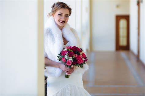 하얀 드레스와 판 쵸에 스마트 소녀 창 미소에 의해 의미합니다 모델의 핑크색과 붉은 장미 꽃다발을 보유 하 고 그녀의 립스틱과 결합 되어 그녀의 손에 겨울에 대한 스톡 사진