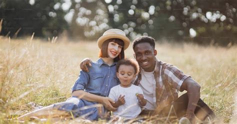 아프리카계 미국인 아버지와 백인 어머니는 귀여운 어린 아들과 함께 여름 피크닉을 즐기고 있습니다 잔디밭에 앉아 진심으로 웃고 있는 아름다운 가족 휴식과 사랑의 개념