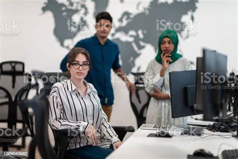 다민족 스타트업 비즈니스 팀 인 아라비아 여성이 노트북과 데스크톱 컴퓨터에서 작업하면서 현대 오픈 플랜 사무실 인테리어 브레인 스토밍에서 회의에 히잡을 착용하고 있습니다