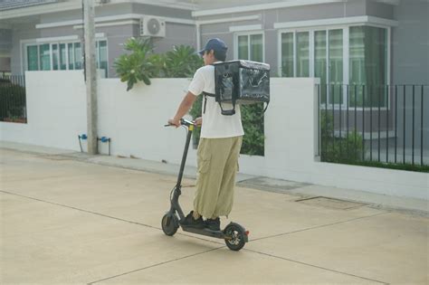 전기 스쿠터를 타고 열 배낭을 멘 웃는 배달원이 온라인 개념을 전달합니다 사진 Unsplash의 수송 이미지