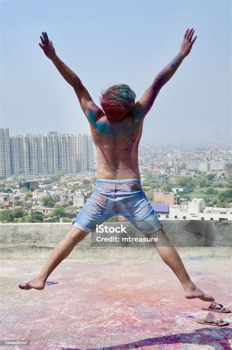 그림은 인도 델리의 옥상에 있는 색상의 홀리 축제에서 힌두교 인도 남자의 이미지 스타 점프 데님 청바지 반바지를 입고 거수 도약 운동에 대한 스톡 사진 및 기타 이미지