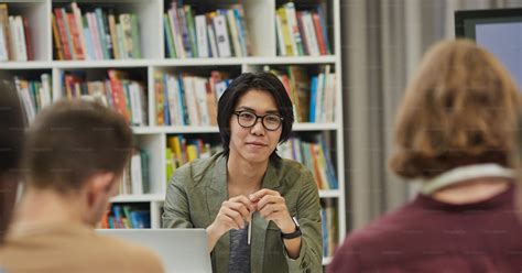 테이블에 앉아 대학 도서관에서 학생들과 이야기를 나누는 청년 사진 Unsplash의 러시아 이미지