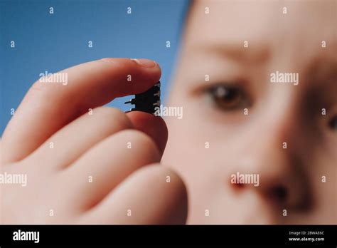 A Girl Holds In Her Hand And Examines A Small Black Chip Chipization