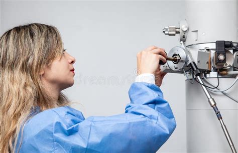 Young Female Scientist Loading A Specimen Using A Sample Holder Into A