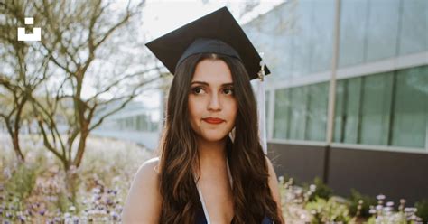 낮 동안 녹색 잎 나무 근처에 서 있는 검은색 학술 모자를 쓴 검은색 학술 드레스를 입은 여자 사진 Unsplash의 무료 졸업 이미지