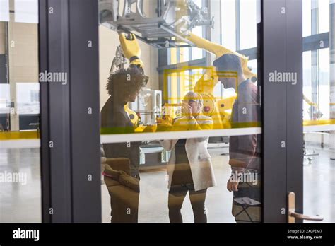 group of engineers work together on programming a robotic arm in a