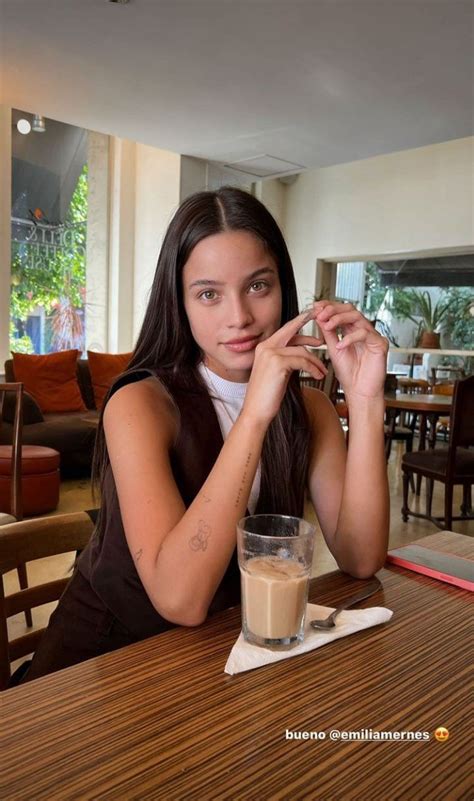 A Woman Sitting At A Table With A Drink