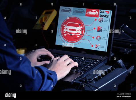 Mechanic with laptop near car engine. Modern car diagnostic program on screen. Car service ...