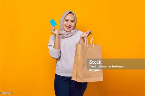 쇼핑백을 들고 노란 배경에 신용 카드를 보여주는 쾌활한 아시아 여성의 초상화 25 29세에 대한 스톡 사진 및 기타 이미지 25 29세 가리키기 가방 Istock