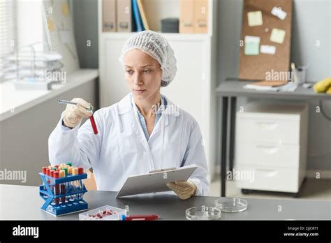 Portrait Of Female Lab Technician Mixing Liquid In Test Tube While Working With Blood Analysis