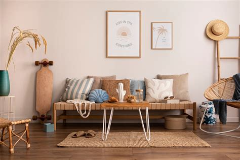 세련된 소파 베개 커피 테이블 모형 포스터 프레임 장식 가구 및 개인 액세서리가있는 거실의 햇살이 잘 드는 밝은 공간 아늑한 가정 장식 템플렛 여름 분위기 집에 대한 스톡