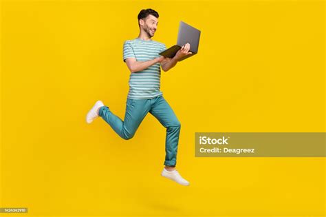 노란색 배경에 고립 된 노트북 착용 티셔츠 청바지 운동화로 달리는 감동적인 남자의 프로필 전체 길이 사진 점프에 대한 스톡 사진 및 기타 이미지 Istock