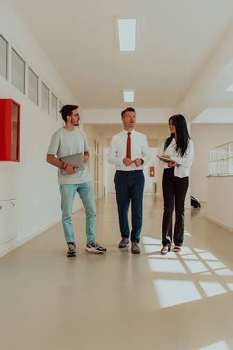 감독은 대기업의 현대적이고 넓은 복도에서 비서 및 젊은 프로그래머와 대화를 나누며 다양한 비즈니스 주제와 프로젝트에 대해 논의합니다 감독에 대한 스톡 사진 및 기타 이미지