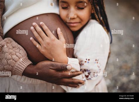 Smiling Black Mix Race Girl Hugging Black Pregnant Mom Belly Stock