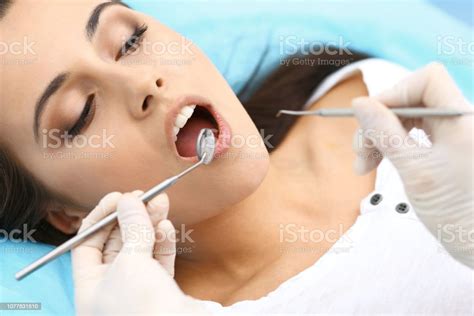 젊은 여성 환자는 치과 의사 사무실 방문 건강 바로 화이트 치아 치아에서 일 하는 의사는 동안 구강 검 진 기간 동안 오픈 입으로 치과 자에 앉아 아름 다운 여자 치과 구강
