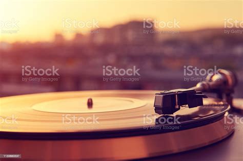 빛 도시 일몰의 배경에 턴테이블 비닐 레코드 플레이어 Dj가 재생 음악을 혼합 하는 사운드 기술 블랙 비닐 레코드 빈티지 비닐