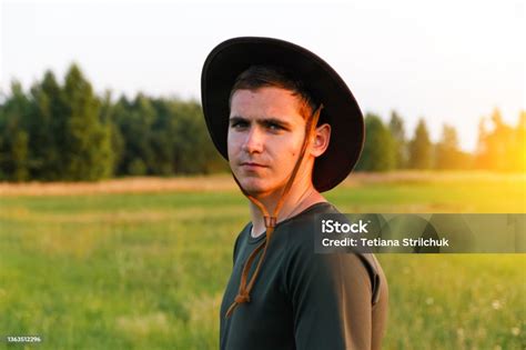일몰에 농업 분야에서 카우보이 모자에 젊은 남자 농부 태양 플레어 모자를 쓴 밀레니엄 세대 의 초상화 잔디 배경에 서 초원에서 야외 농업수확 개념 20 24세에 대한 스톡