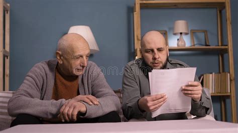 Elderly Father And His Adult Son Discussing Paper Documents Together At Home Stock Footage