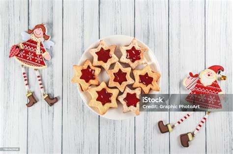 잼으로 채워진 수제 스타 쿠키의 상단보기는 소박한 흰색 나무 테이블에 접시에 배치 딸기 라즈베리 건포도 잼 쿠키 천사와 산타 클로스의 크리스마스 장식 진저브레드 비스킷에