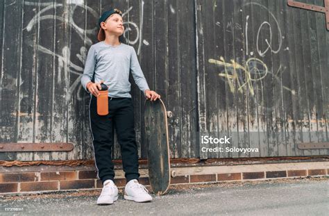 스케이트 보드와 물 병 플라스크와 나무 그런 지 낙서 벽 옆에 서 십대 스케이트 보더 소년 청소년 세대 자유 시간 지출 개념 이미지입니다 소년에 대한 스톡 사진 및 기타