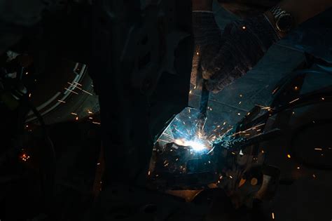 클로즈업 보기 강한 사람은 용접기 금속 제품은 차고 작업장에서 용접 기계와 용접 파란색과 오렌지 불꽃은 차체 수리 자동차 동안 측면에 비행 자동차 서비스 산업 강철에 대한