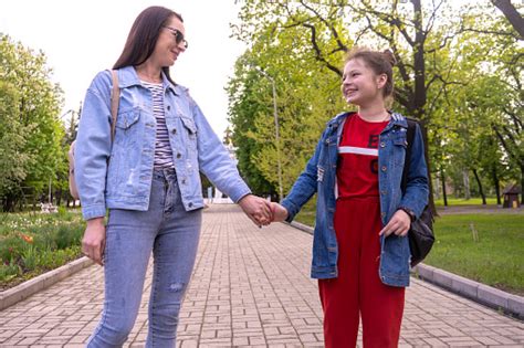 어머니와 십대 딸이 공원에서 걷고 손을 잡고 긴 머리와 십대 소녀가 도시에서 놀고있는 행복한 젊은 백인 여성 라이프 스타일 가족 10 11세에 대한 스톡 사진 및 기타