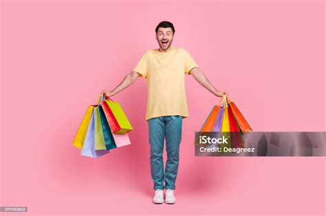 긍정적 인 놀란 남자의 전체 길이 사진 기뻐하다 세련 된 옷 홀드 팩 돈을 쓰다 부티크 절연 통하고 분홍색 배경 35 39세에