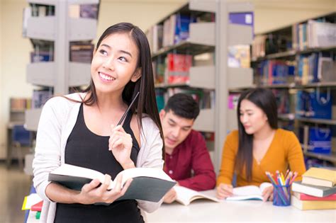 전경에 있는 여자는 책을 읽고 있습니다 젊은 아시아 여자는 현대 도서관에서 읽고 있다 교육 개념을 가진 사람들입니다 귀여운에 대한 스톡 사진 및 기타 이미지 Istock