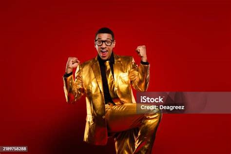 생생한 빨간색 배경과 반짝이는 황금 양복을 입은 역동적인 청년이 활기차고 카리스마 넘치는 포즈로 성공을 축하합니다 30 34세에 대한 스톡 사진 및 기타 이미지 Istock