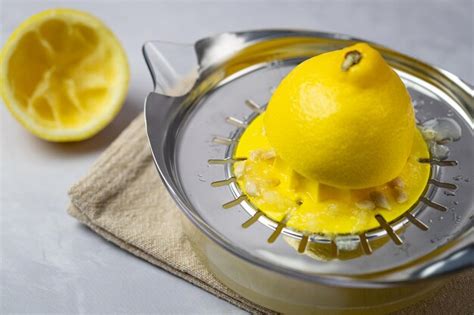 Premium Photo | Squeezing lemon using a manual kitchen squeezer view from above