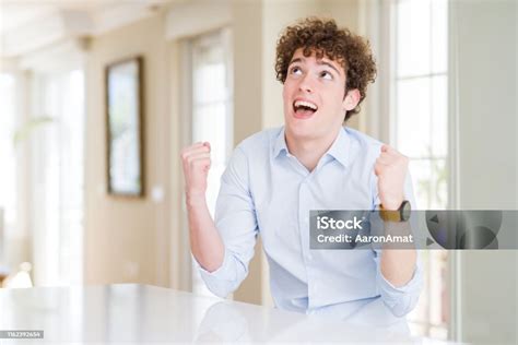 곱슬 곱슬 한 젊은 사업가는 팔을 들고 눈을 감고 성공에 놀랐고 축하하는 머리를 읽었습니다 우승자 컨셉 매우 기쁜에 대한 스톡 사진 및 기타 이미지 Istock