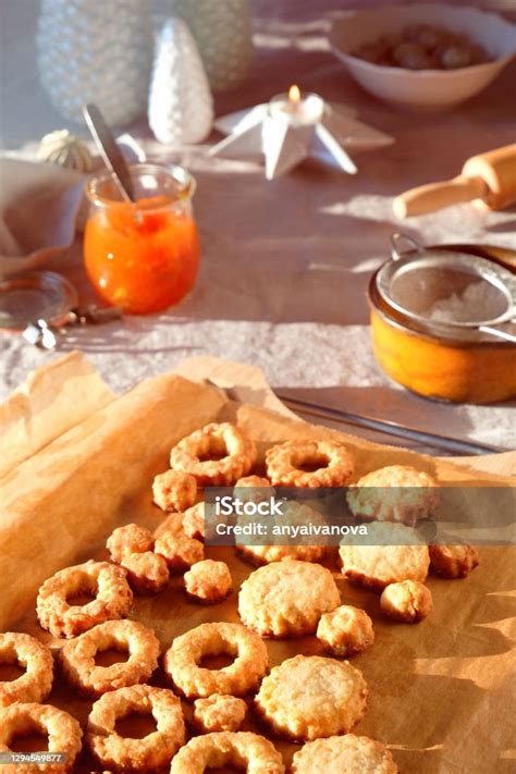 냉각 랙과 빈티지 금속 접시에 오렌지 잼으로 가득 크리스마스 린저 쿠키 천연 린넨 식탁보가 있는 테이블에 있는 Xmas 스톨렌 장식과 향신료 자연 햇빛 강림절에 대한 스톡
