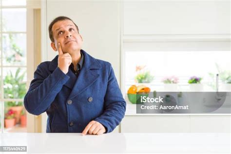 중년 남자는 질문에 대해 생각 턱에 손으로 집에 앉아 펜시브 표현 사려 깊은 얼굴로 미소 의심 개념 나이에 대한 스톡 사진 및 기타 이미지 Istock