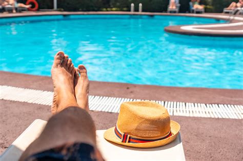 물이 내려다보이는 갑판 의자에 앉아 휴식을 취하는 남자의 다리 모자를 쓰고 수영장 옆에서 일광욕을 하는 남자의 다리 40 44세에 대한 스톡 사진 및 기타 이미지 Istock