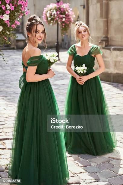 두 아름다운 신부 들러리 여자 금발과 갈색 머리 숙녀 우아한 전체 길이 오프 숄더 그린 쉬폰 신부 들러리 드레스와 들고 꽃다발을 입고 꽃과 결혼식 날을위한 유럽 의 구시