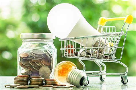 금융 에너지와 환경 개념을 절약에 대 한 자연 녹색 배경 흐리게에 대 한 유리 항아리에 돈 동전과 빛나는 전구 Led 램프 미니 쇼핑 카트 또는 트롤리 Led 조명에 대한