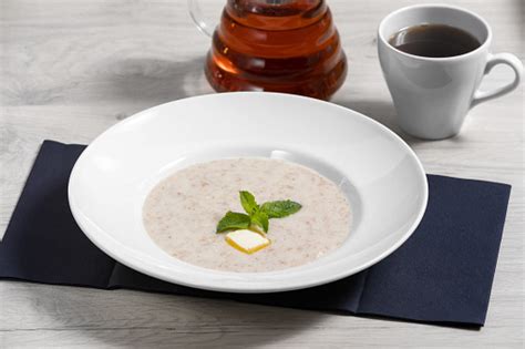 버터와 민트 잎이 달린 흰색 접시에 우유 죽을 차 한 잔과 함께 나무 배경에 놓습니다 건강한 아침 식사 적절한 아침 0명에 대한 스톡 사진 및 기타 이미지 Istock
