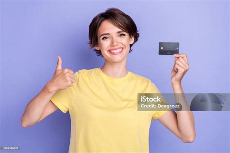 젊은이 사랑 스럽다 화려한 멋진 좋은 여자 노란색 티셔츠를 입고 엄지 손가락 위로 이빨 추천 은행 보라색 배경에 고립 된 은행을