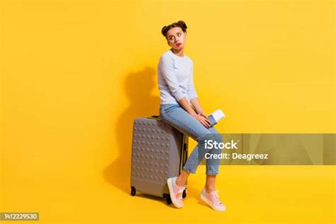 불행한 예쁜 아가씨의 전체 길이 사진 긴 소매 좌석 수하물을 입고 빈 공간 고립 된 노란색 배경 관광객에 대한 스톡 사진 및