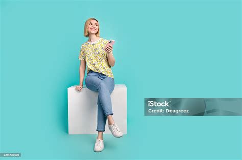 흥분한 꿈꾸는 아가씨 착용 꽃 프린트 티셔츠 문자 메시지 현대 장치 빈 공간 외딴 청록색 배경의 전체 길이 사진 Brand Name Smart Phone에 대한 스톡 사진