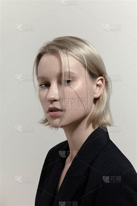 年轻的金发女子，短直发，黑色套装戏剧性的灯光肖像