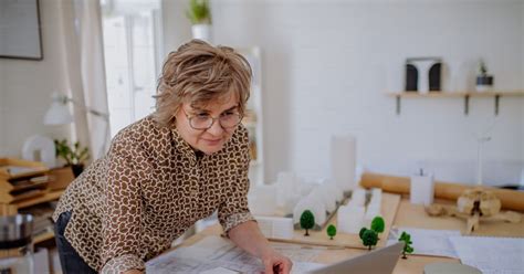 사무실에서 청사진을 보고 있는 주택 모델을 가진 선임 여성 건축가 사진 Unsplash의 기업가 이미지