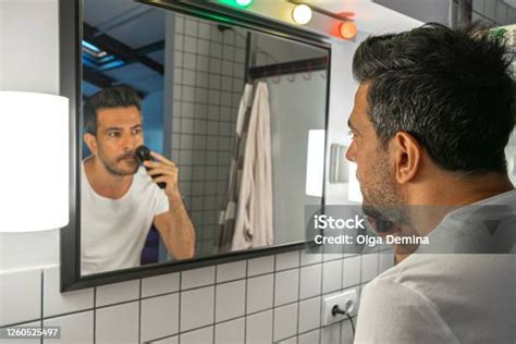 잘 생긴 수염 남자는 욕실 거울 앞에서 트리머 기계와 그의 수염과 콧수염을 면도 가정 생활에 대한 스톡 사진 및 기타 이미지 가정 생활 거울 기계류 Istock