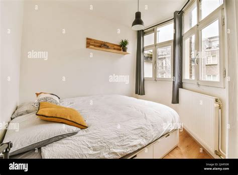 Minimalist Interior Design Of Small Bedroom With Soft Bed Placed In Corner And Wooden Wardrobe