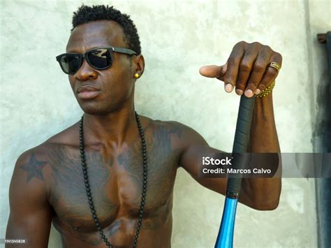 젊은 매력적이 고 잘 생긴 흑인 아프리카계 미국인 남자에 맞는 근육 질의 몸과 여섯 팩을 들고 야구 방망이를 포즈 멋진 늠 름 한와 나쁜 소년 태도의 도시 라이프 스타일