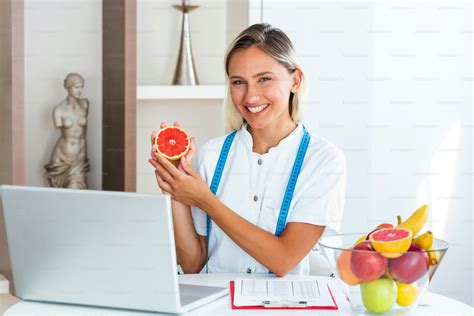 상담실에서 웃고 있는 젊은 여성 영양사의 초상화 건강한 과일 주스 측정 테이프가 있는 영양사 책상 다이어트 계획을 세우는 영양사 사진 Unsplash의 사무실 이미지