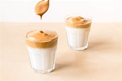 달곤에서 커피를 만드는 방법 단계별 사진 지시 7단계 우유에 크림을 넣으세요 재료 인스턴트 커피 설탕 물 우유 및 나무 배경에 채찍질을위한 거품기 귀리 우유에 대한 스톡