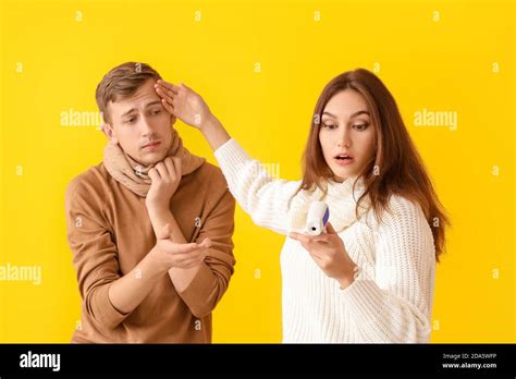 Woman Measuring Temperature Of Her Husband On Color Background Stock Photo Alamy