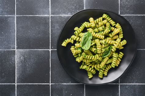 페스토와 이탈리아 푸실리 파스타 검은 돌 조리대 배경에 검은 접시에 바질 페스토와 허브 파르 메산 치즈 바질 및 마늘을 곁들인 Fusilli 파스타 상단 보기 공간을