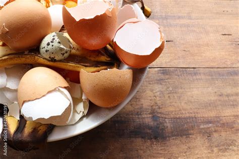 Banana Skin Eggshell And Orange Peels In White Bowl On Wooden Table